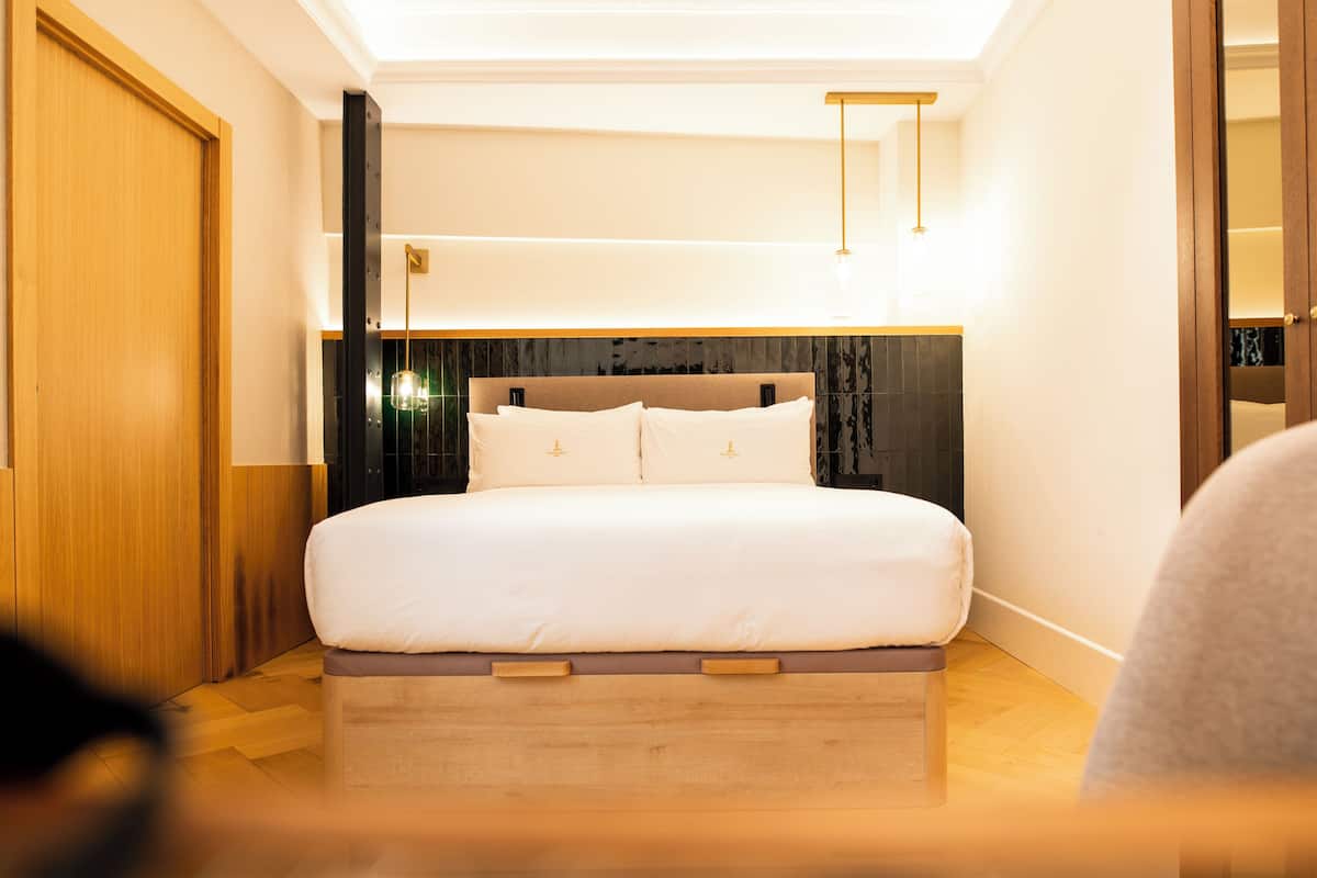 Quarto moderno com uma cama grande, piso de madeira e design minimalista.