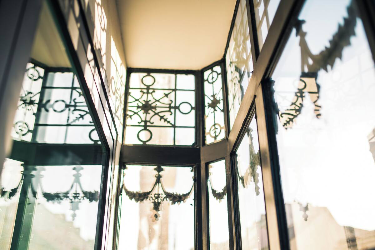 Canto de um quarto com grades de metal ornamentadas e um lustre.