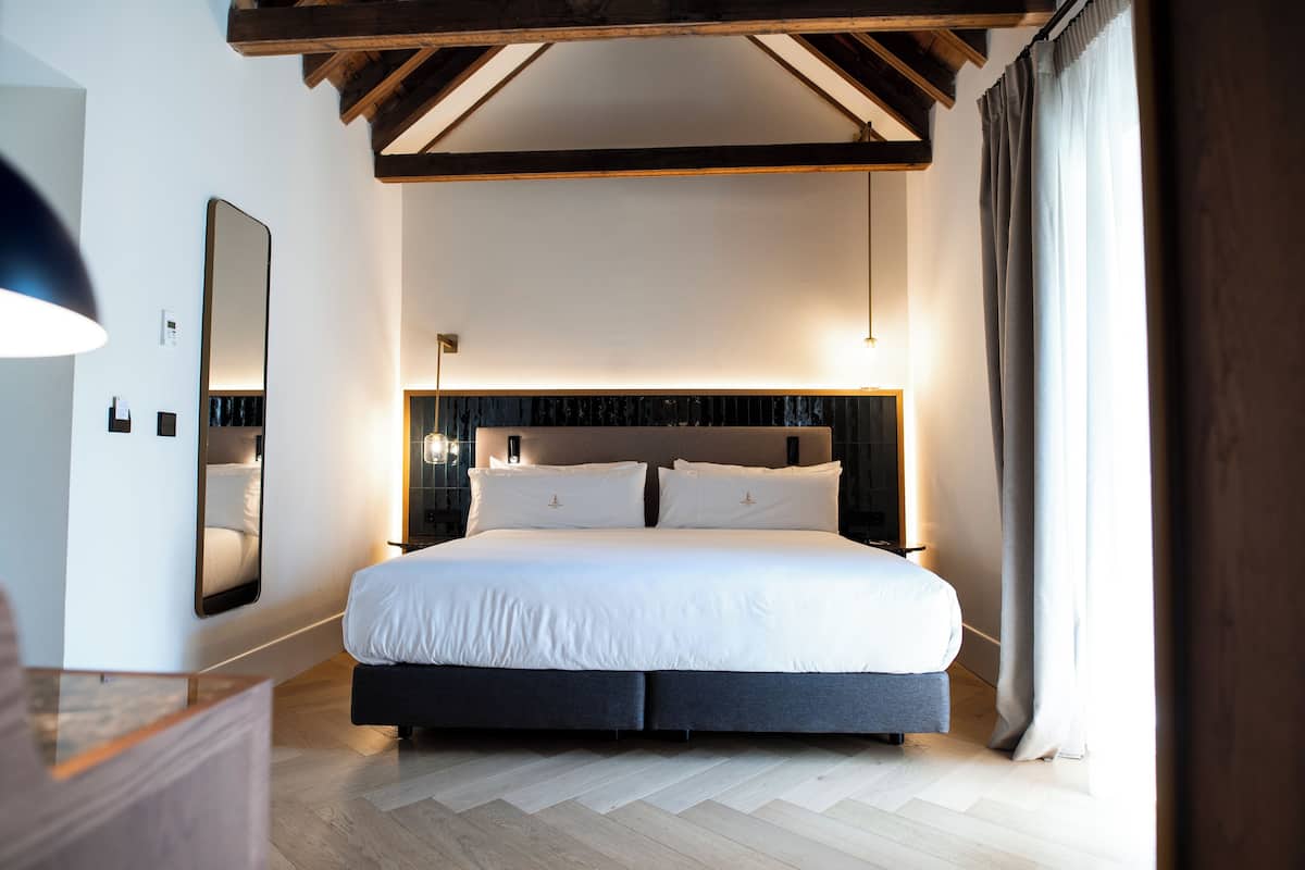 Um quarto moderno com uma cama grande, teto de madeira e um espelho grande na parede.