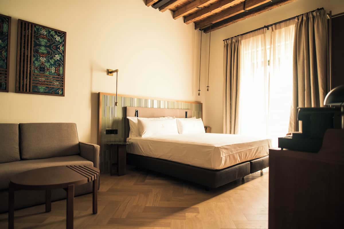 Quarto de hotel com uma cama, um sofá, uma mesa e um piano.