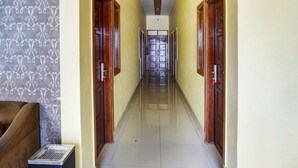 Um corredor com portas de madeira, parede estampada e chão de azulejos.