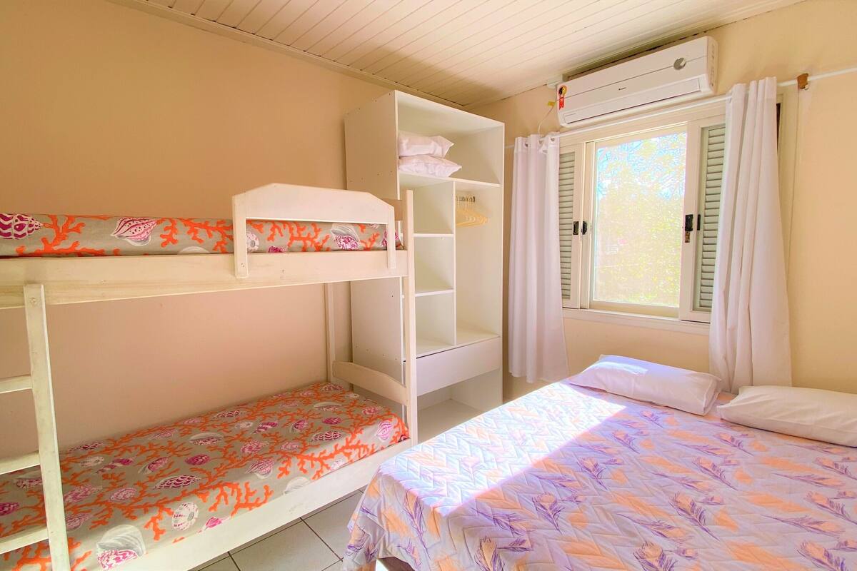 Quarto com beliche, janela, cortinas e ar condicionado.