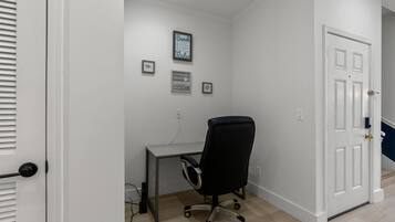 Quarto com escrivaninha, cadeira de escritório preta e porta branca.