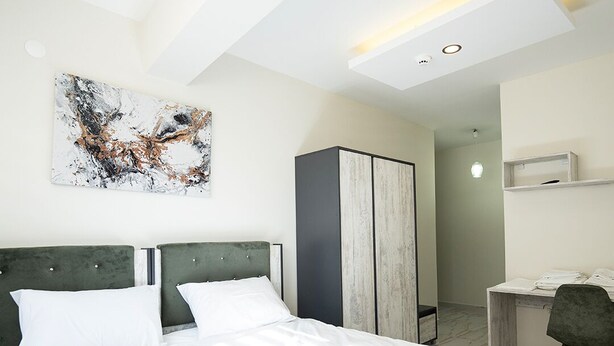 Quarto moderno com uma cama grande, um guarda-roupa e uma escrivaninha com cadeira.