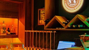 Uma área de bar com um letreiro para Jack Daniel's No. 7 Tennessee Whiskey, prateleiras com garrafas, um laptop e um teclado sobre uma superfície de madeira.