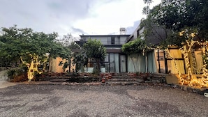 Uma casa com um caminho de pedra que leva à entrada, rodeada por vasos de plantas e árvores.