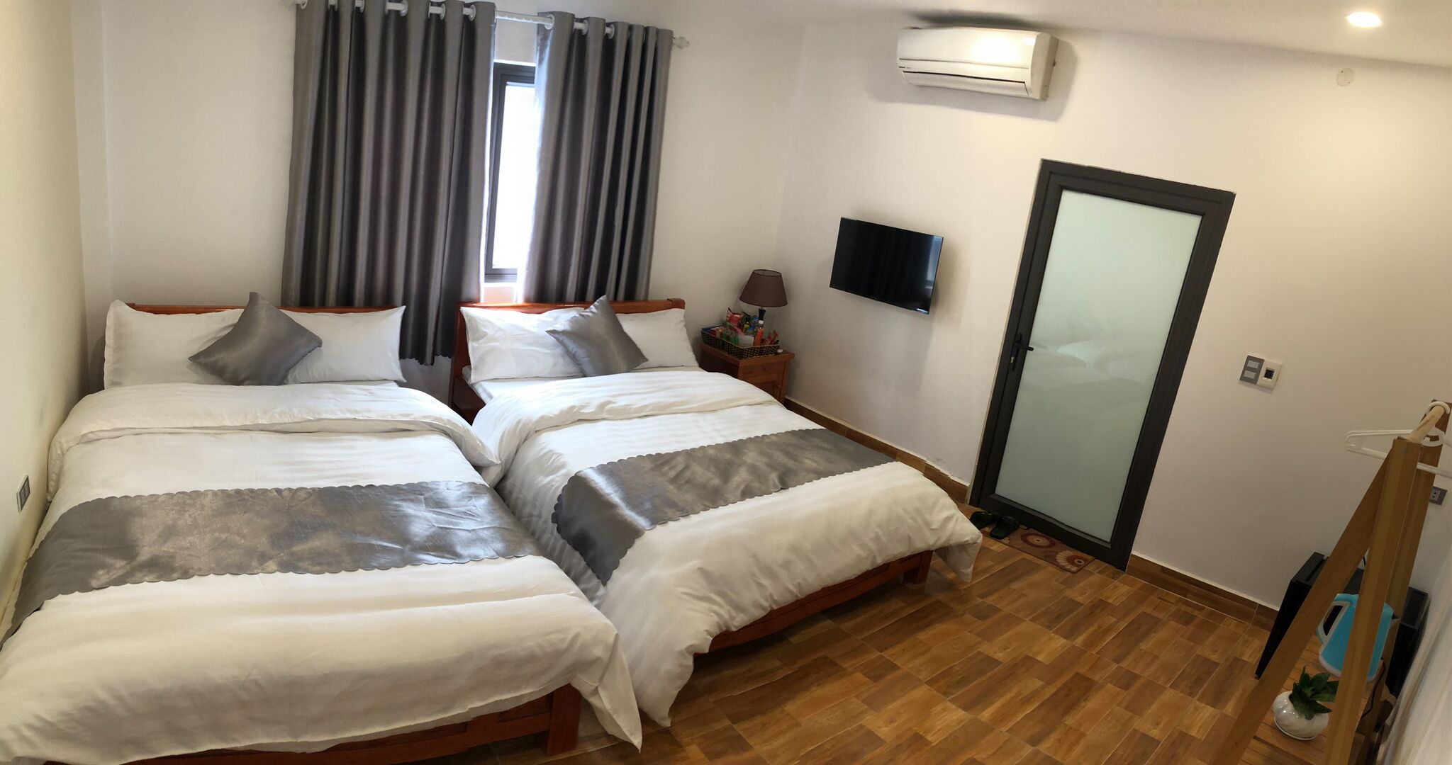 Quarto de hotel com duas camas, televisão, aparelho de ar condicionado e porta deslizante.