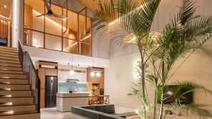 Um interior moderno com escada, cozinha e área de estar com uma grande planta.