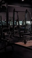 Uma academia com equipamentos de musculação, espelhos e máquinas de exercício.