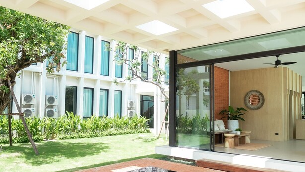 Um edifício moderno com um pátio, um elemento aquático e uma área de estar com uma planta.