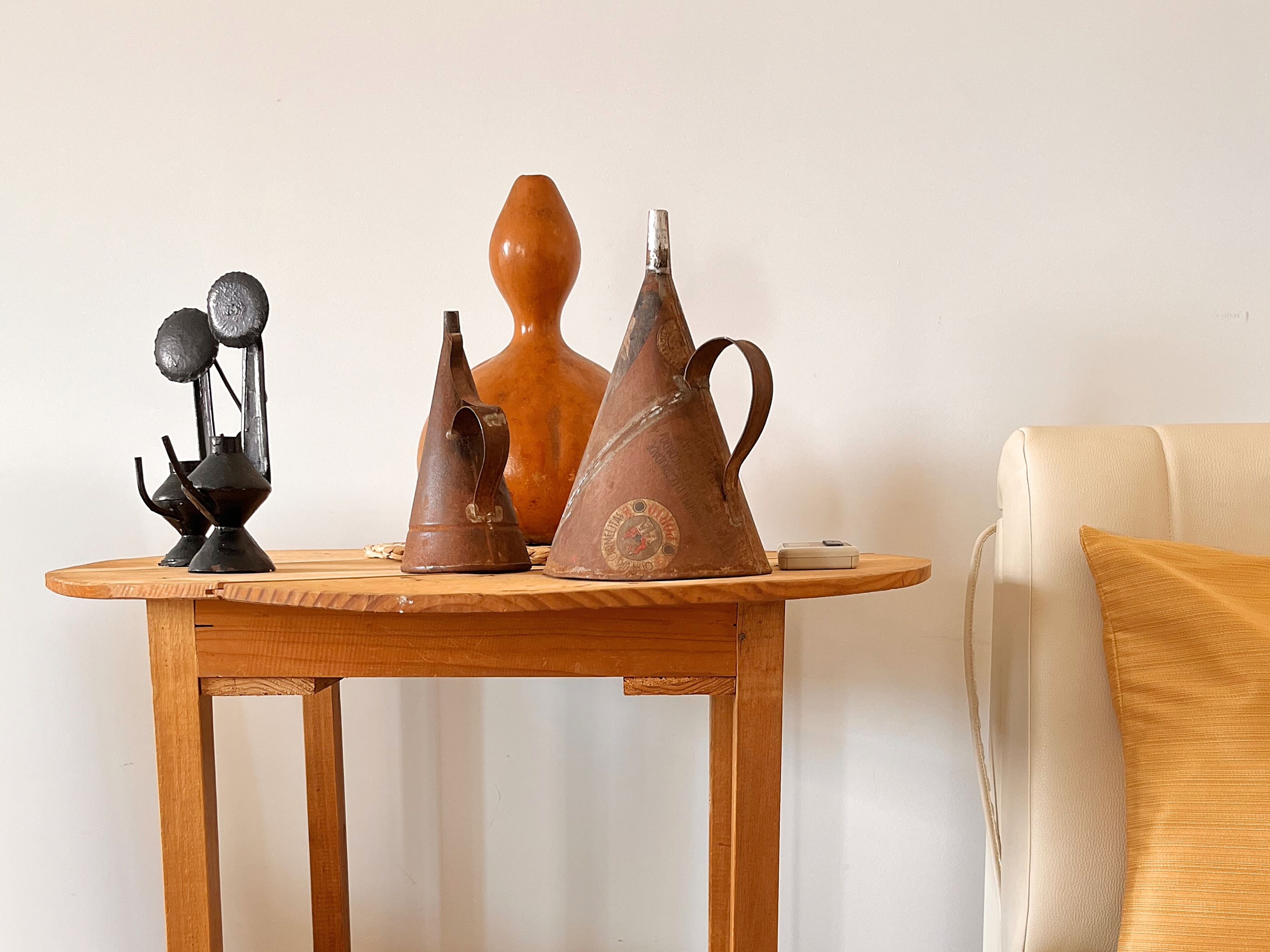 Uma mesa de madeira com três objetos de cerâmica e um pequeno aparelho eletrônico.