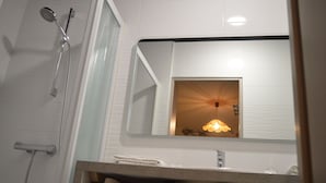 Casa de banho com chuveiro, lavatório e espelho.