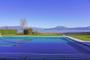 Uma piscina com vista para montanhas e um corpo d'água ao longe.