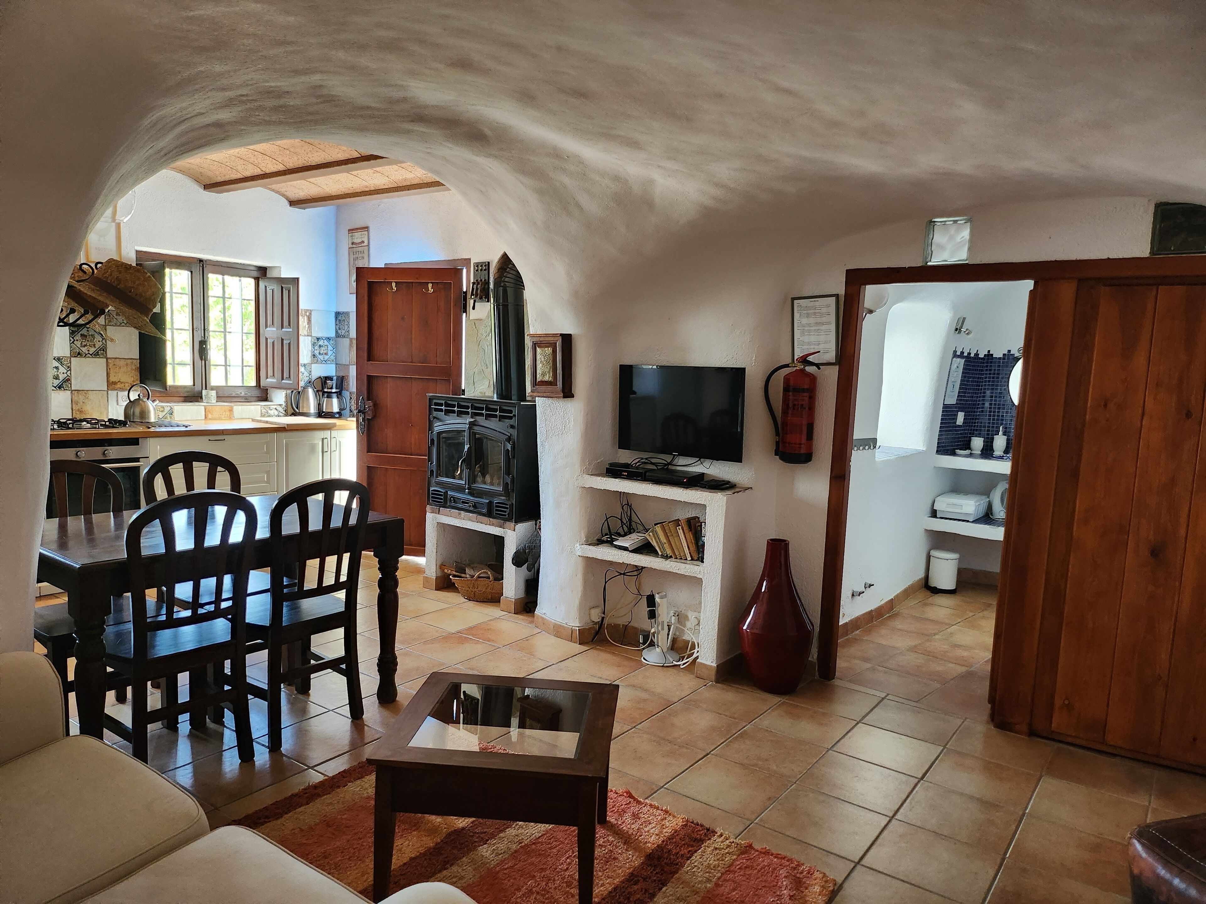 Uma sala de estar acolhedora com lareira, uma área de jantar e uma cozinha visíveis através de um arco.