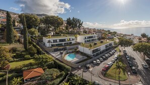 Um bairro residencial com casas modernas, uma piscina e uma rua com carros estacionados.