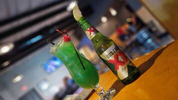Um bar com um cocktail verde e uma garrafa com o rótulo "DOS EDOU" sobre uma superfície de madeira.