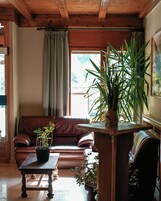 Uma sala de estar aconchegante com um sofá de couro, uma mesa de centro de madeira e uma grande planta em vaso.