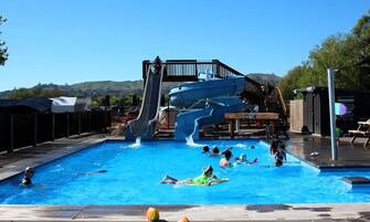 Piscina com escorregador e área de deck de madeira.