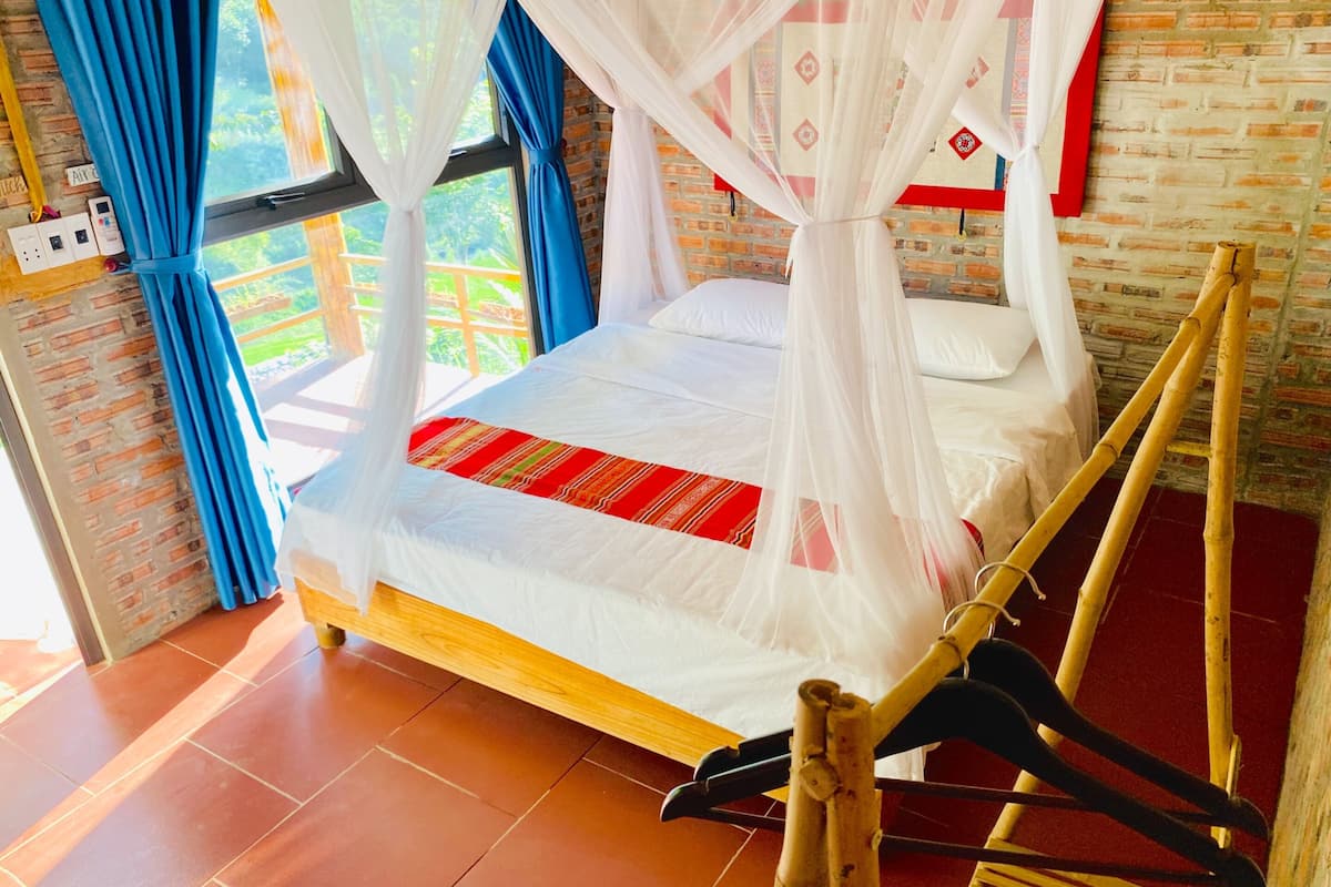 Uma cama com dossel branco, um travesseiro listrado em vermelho e branco, e um edredom com padrão vermelho e branco.