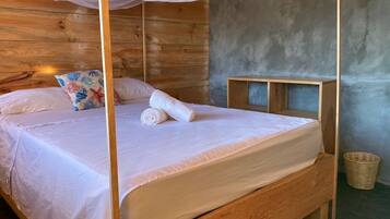 Uma cama de madeira com dossel, roupa de cama branca e almofada decorativa.
