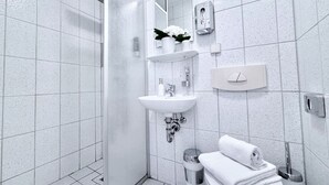 Uma casa de banho moderna com chuveiro, lavatório e sanita.
