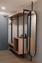 Quarto compacto com escrivaninha, cabideiro, espelho e porta.