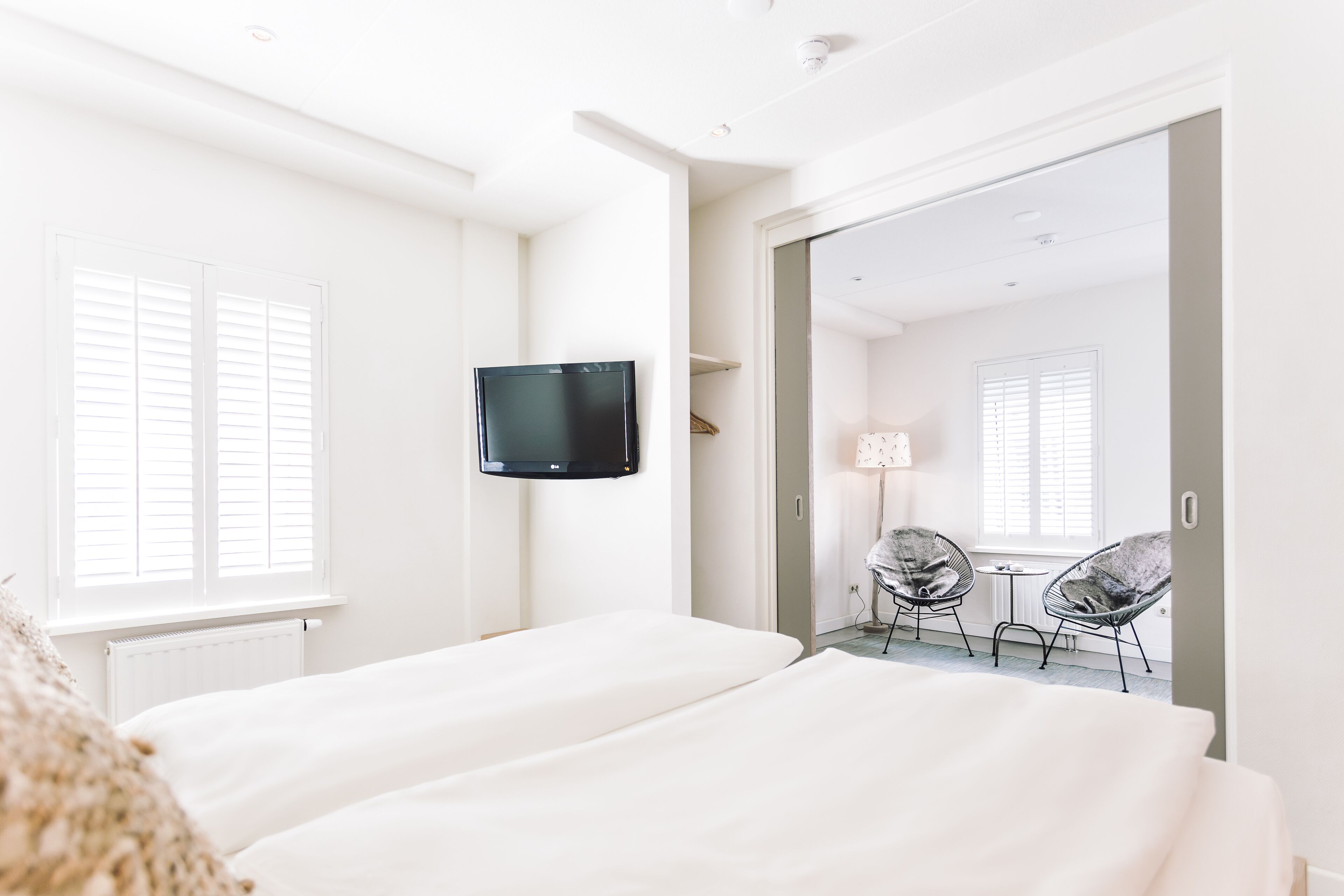 Quarto de hotel com duas camas, uma televisão de tela plana, um espelho e duas cadeiras.