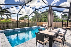 Piscina descoberta coberta com um deck de madeira, espreguiçadeiras e uma mesa com cadeiras.