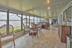 Um alpendre coberto com uma mesa de jantar e cadeiras, um sofá e uma televisão.