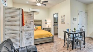 Quarto com cama, escrivaninha e cadeira. Há um ventilador de teto e ar condicionado.