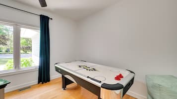 Quarto com mesa de bilhar, janela com cortinas e um banco estofado verde.