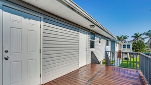 Um edifício residencial com deck de madeira, revestimento branco e porta de garagem.