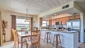 Uma cozinha moderna com armários de madeira, uma geladeira de aço inoxidável e uma ilha grande com banquetas.