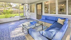 Uma sala de estar ampla com um sofá azul, uma mesa de centro de vidro e um tapete estampado.