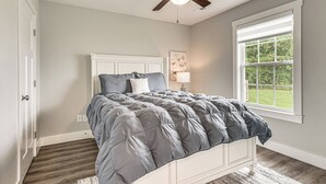 Quarto com cama, ventilador de teto, janela e porta.