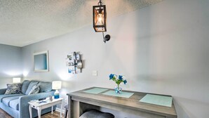 Sala de estar com sofá, mesa de centro, pequena mesa com abajur e luminária na parede.