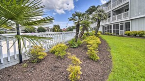 Um jardim bem cuidado com diversas plantas e um cercado branco.