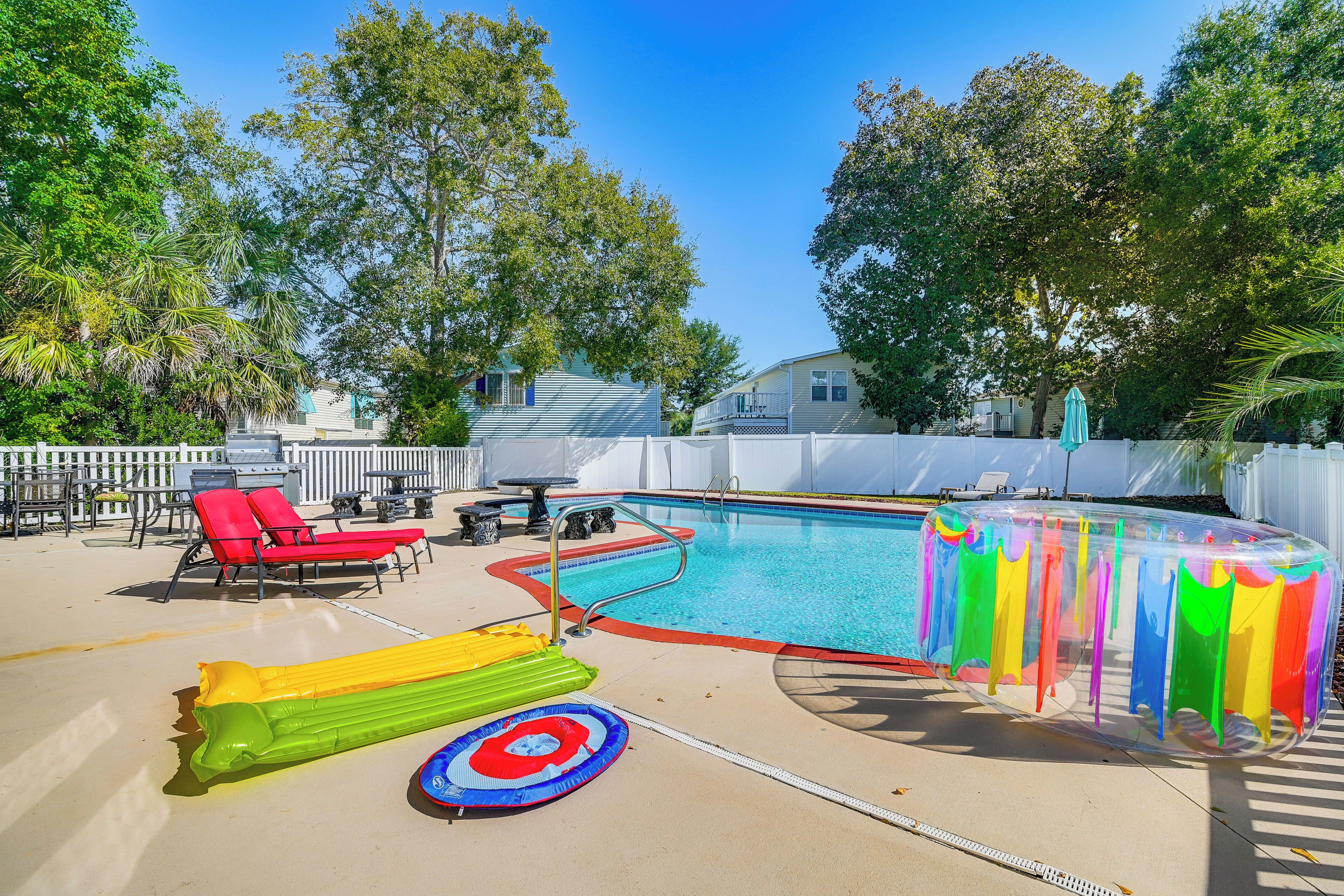Uma piscina com brinquedos infláveis e espreguiçadeiras.