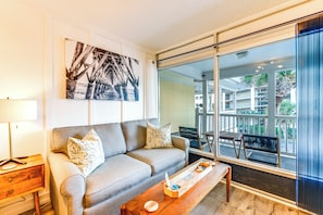 Sala de estar moderna com sofá, mesa de centro e uma grande janela com vista para o exterior.