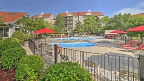 Hotel com piscina, guarda-sóis vermelhos e espreguiçadeiras.
