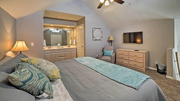 Quarto com cama, cômoda, cadeira, escrivaninha, ventilador de teto e espelho.