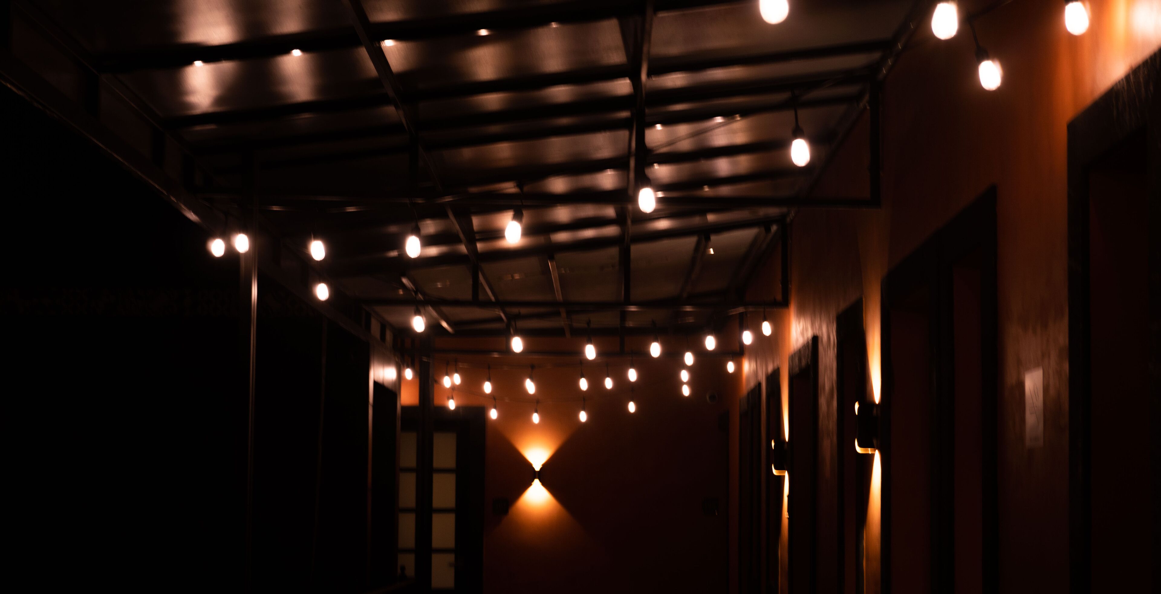 Um corredor com teto de vigas aparentes e luminárias penduradas.