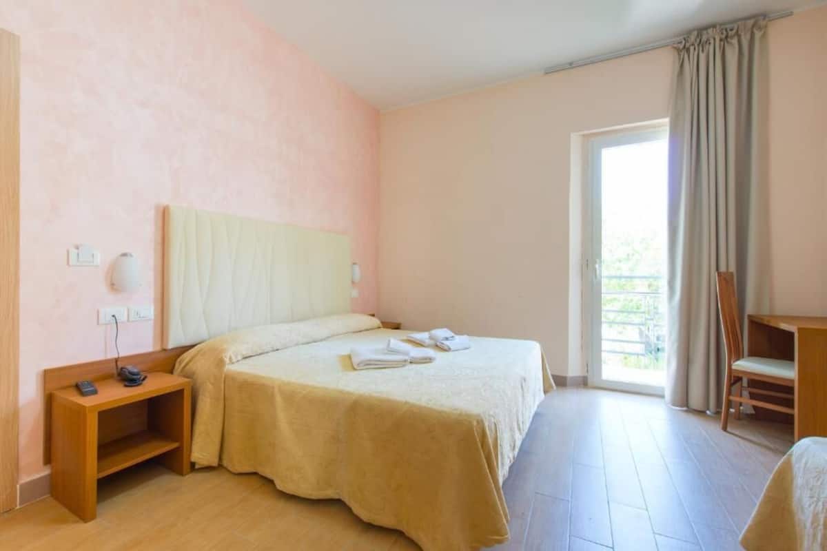 Quarto de hotel com uma cama, mesa de cabeceira e uma cadeira.
