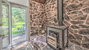 Quarto com paredes de pedra, lareira, porta de vidro para um deck e um letreiro de boas-vindas.