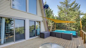 Um terraço com móveis de exterior, uma mesa de vidro e uma área de piscina.