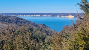 Vista de um lago rodeado por colinas arborizadas.