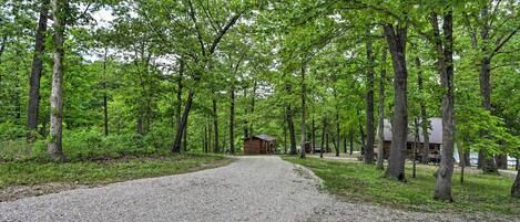 Um caminho de cascalho leva a uma cabana rodeada por árvores.
