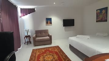 Quarto de hotel com uma cama, uma cadeira, uma televisão e um quadro na parede.