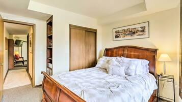 Quarto com cama de madeira, mesa de cabeceira, criadeira, quadro na parede e armário.