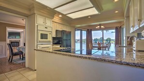 Cozinha moderna com uma ilha grande, eletrodomésticos embutidos e vista para um lago.